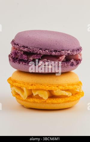 Two vibrant macarons, one yellow and one pink, are stacked neatly ...