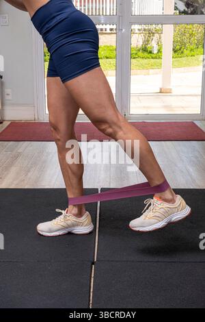 Closeup of woman's legs doing exercise with elastic band for lateral ...