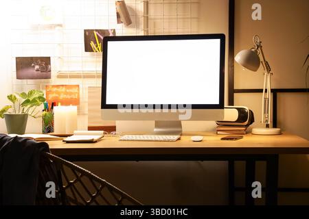 Blank computer monitor with glowing lamp on desk in office at night ...