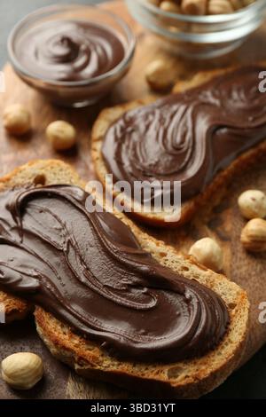 Board of bread with chocolate paste and hazelnuts on wooden background ...