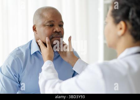 Black male doctor checking lymph nodes of female patient at hospital ...