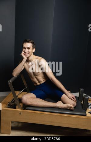 Slim male ballet dancer trains on Pilates equipment. Elegant pose, core ...