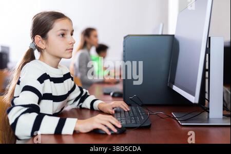 Teen schoolgirl learning basics of programming in computer college ...