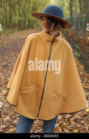 Woman with poncho and hat enjoying white wine in her vineyard at autumn ...