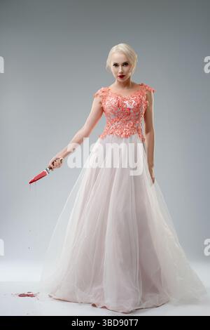 Bride in a blood-stained gown posing elegantly in a studio setting ...