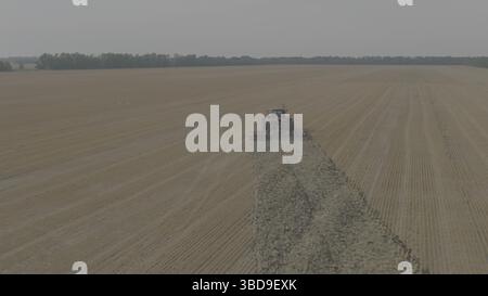Disking the field. Big red Tractor cultivating land of Disc Harrow ...