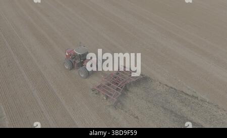 Big red Tractor Pulling Disc Harrow Through Field in Preparation soil ...