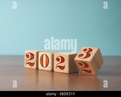 Flipping wooden cubes with the Year number 2022 and 2023 on a magenta ...