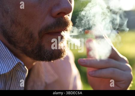 Person smoking a cigarette on a blurred background Stock Photo - Alamy