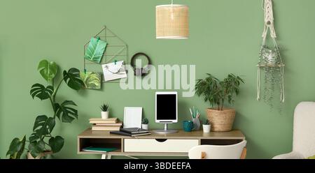 Stylish workplace with computer, books and different houseplants near ...