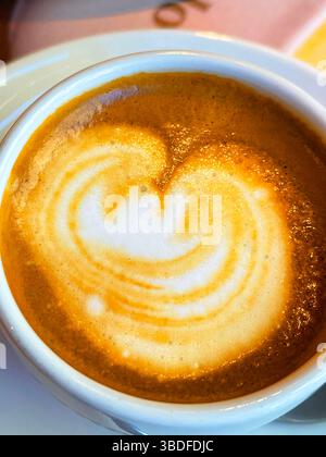 Close-up of creamy heart-shaped latte art in a turquoise cup on a ...