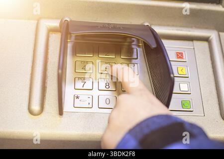 Close-up of hand entering PIN/pass code on ATM/bank machine keypad ...