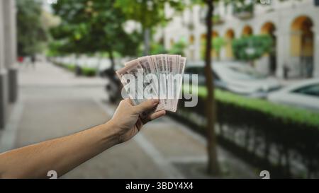 Man holding bangladeshi taka banknotes in hand on a busy city street in ...