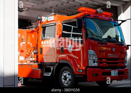 A Tokyo firefighter performs maintenance beside a vibrant red fire ...