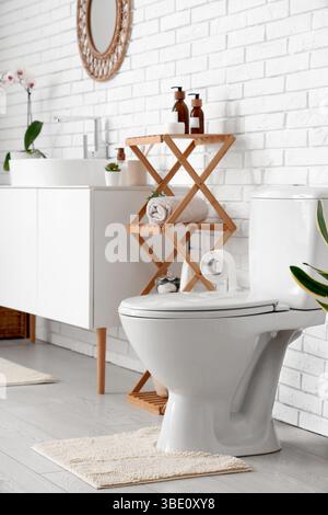 Interior of restroom with toilet bowl and shelving unit near blue wall ...