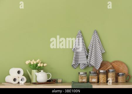 Jars of pasta with teapot, tulips and paper towels on counters near ...