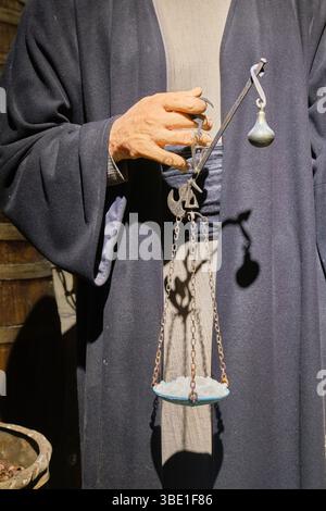 An old man merchant using a hand scale for a buyer at his stall at a ...