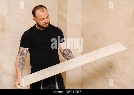 Professional tiler placing large format travertine tiles on bathroom ...