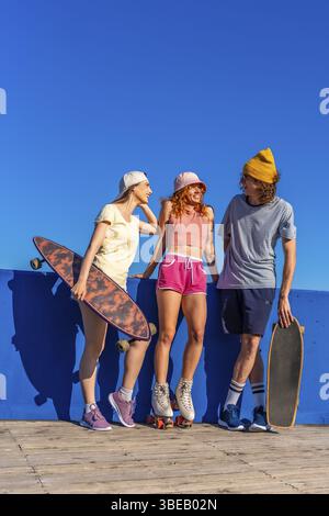 Happy friends are having fun with skates and longboards at straight ...