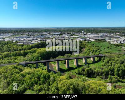 Urban bridge spanning a lush green valley with city skyline in the hazy ...
