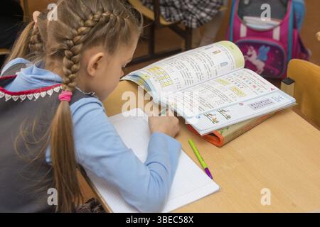 schoolgirl writes lessons in notebook. online learning for laptop Stock ...