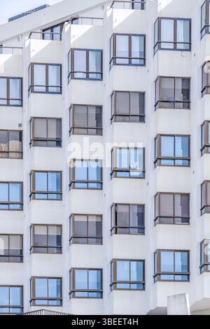 A modern glass building facade displays reflections and contemporary ...