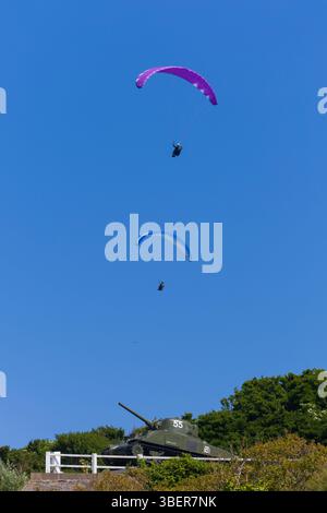 Two paragliders flying over the M4A2 Sherman tank memorial in ...
