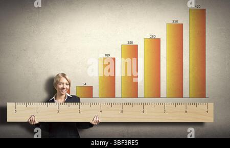 Young businesswoman measuring something with big ruler Stock Photo - Alamy