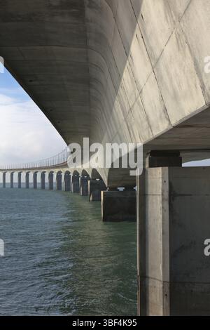 A vertical shot of a highway road with the sea and a blue sky in the ...