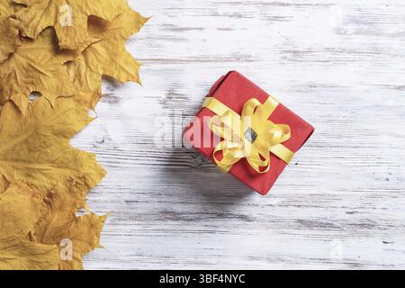 Yellow gift box with bow lies on table amidst glowing tangled led ...