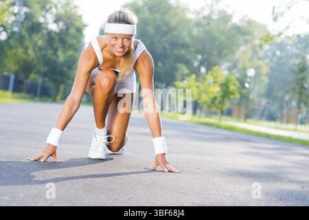 Young woman runner outdoor standing in start pose Stock Photo - Alamy