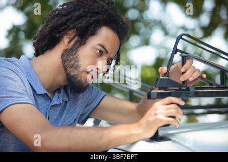 man fixing a car roof rack outdoors Stock Photo - Alamy