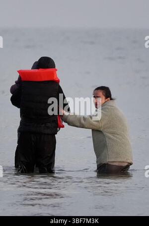 People thought to be migrants wait in the sea to board a small boat in ...