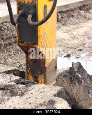 An excavator with jackhammer hydraulic hammer working on smashing lot ...