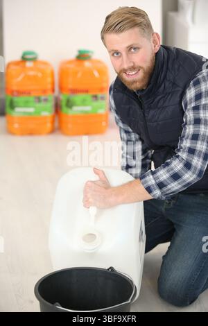 man pouring chemical from container into bucket Stock Photo - Alamy