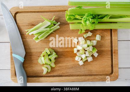 Celery stalks sliced in multiple ways on a wooden board, top view, for ...