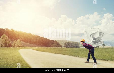 Builder man carrying paper ball on his back Stock Photo - Alamy