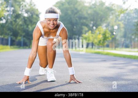 Young woman runner outdoor standing in start pose Stock Photo - Alamy
