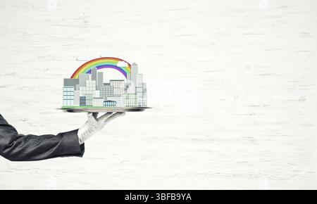 Hand holding metal tray with modern city model against concrete ...