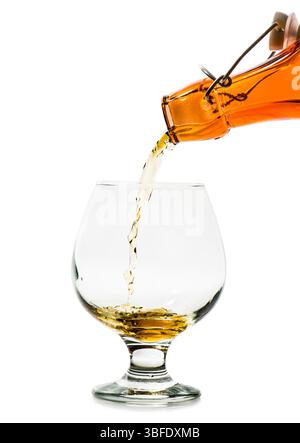 Pouring brandy from a bottle into a glass. Snifter of brandy on a black ...