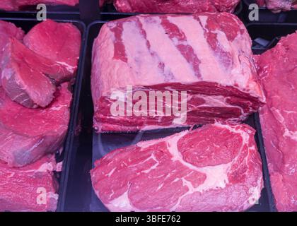 Various cuts of raw beef neatly arranged in a butcher shop display ...