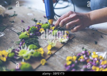 Florist making flower decoration with letters and glue. Indoors natural ...