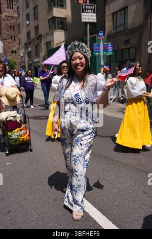 A young woman wearing a crown and sash blows a kiss while holding a ...