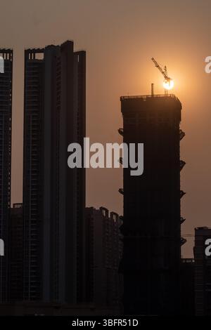 A construction crane stands tall at sunset, its long arms reaching for ...