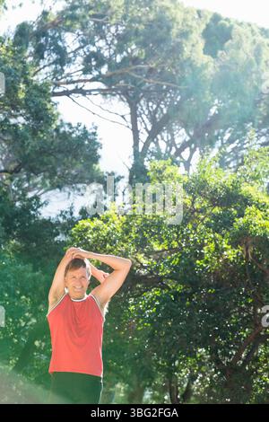 Man stretching arm overhead in studio amid exercise mats, foam rollers ...