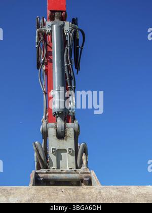 Front view of the boom of an excavator with a bucket against a blue sky ...