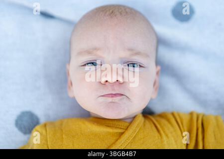 Cute emotional smiling funny newborn boy laying on bed top view. Baby ...