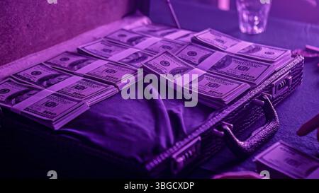 Open briefcase overflowing with stacks of hundred dollar bills bathed ...