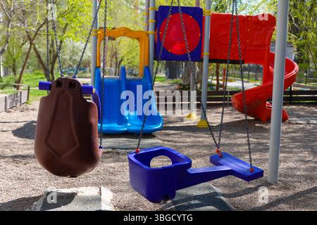 Child swings on playground, surrounded by trees and sunny weather Stock ...