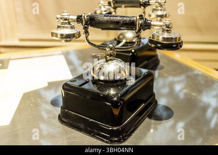 An antique analog telephone set with black box base and golden ringer ...